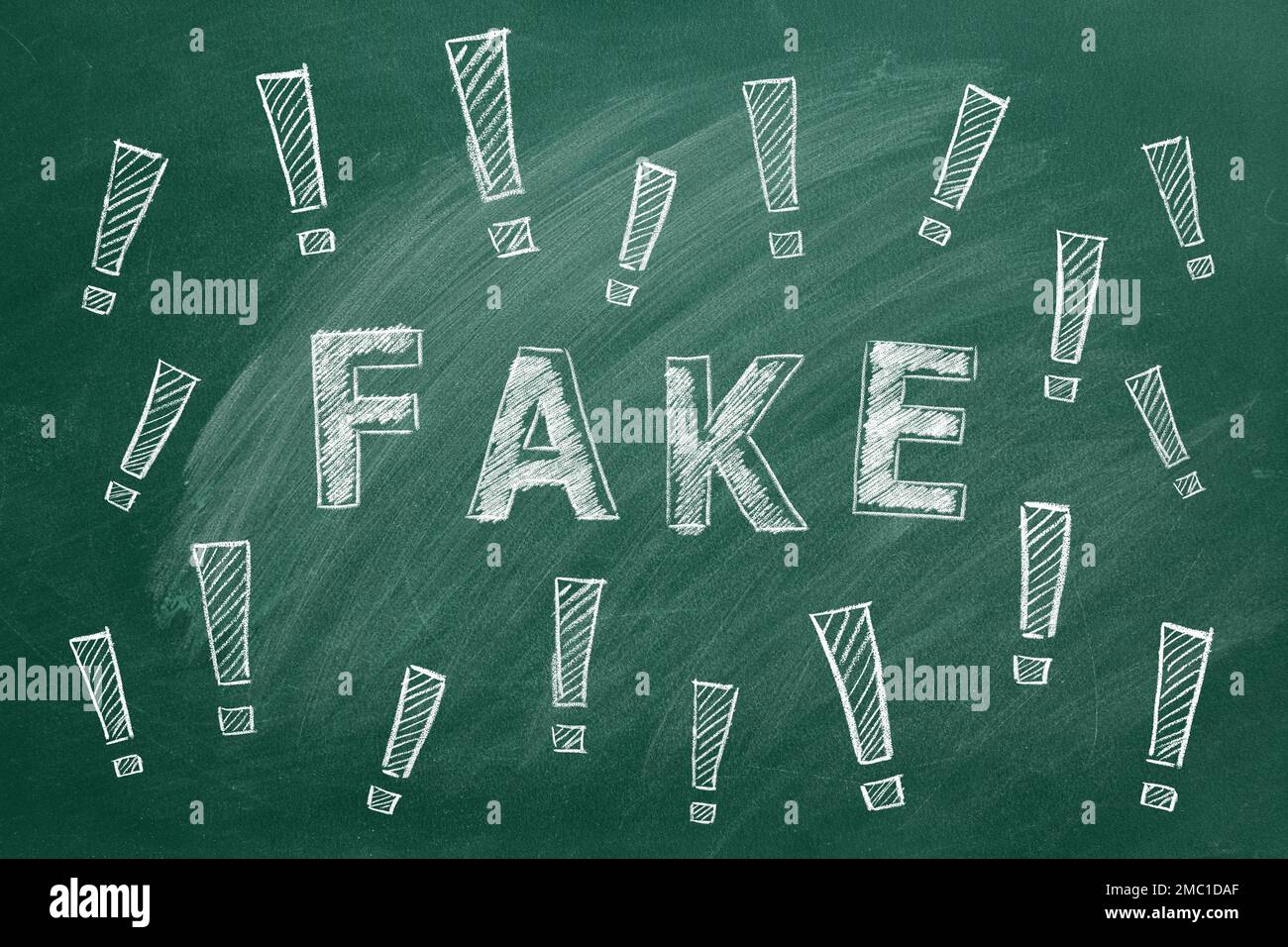 The word FAKE and exclamation marks written in chalk on a greenboard ...
