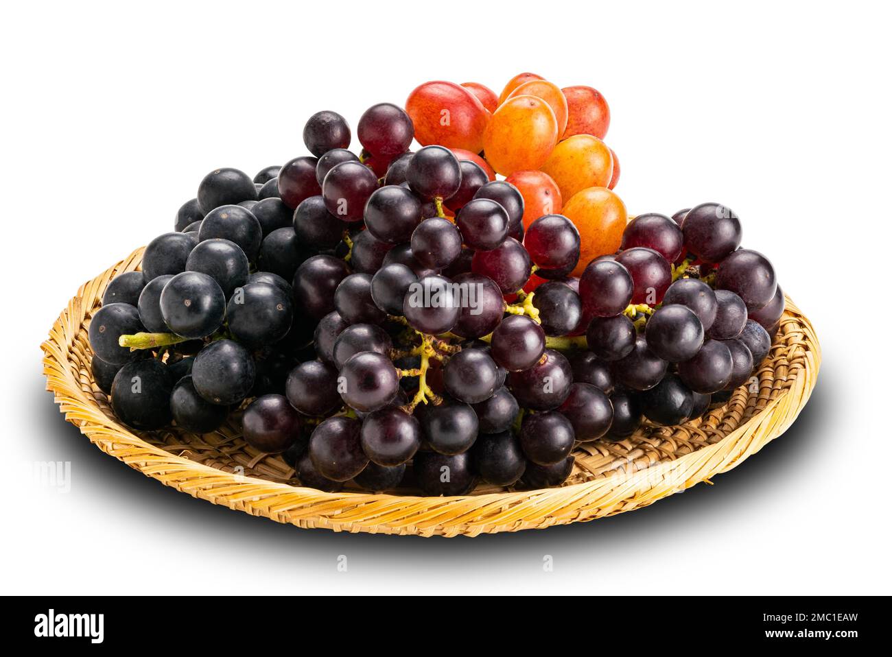 Bunches of ripe red grapes, black grapes and purple grapes in bamboo plate isolated on white ...