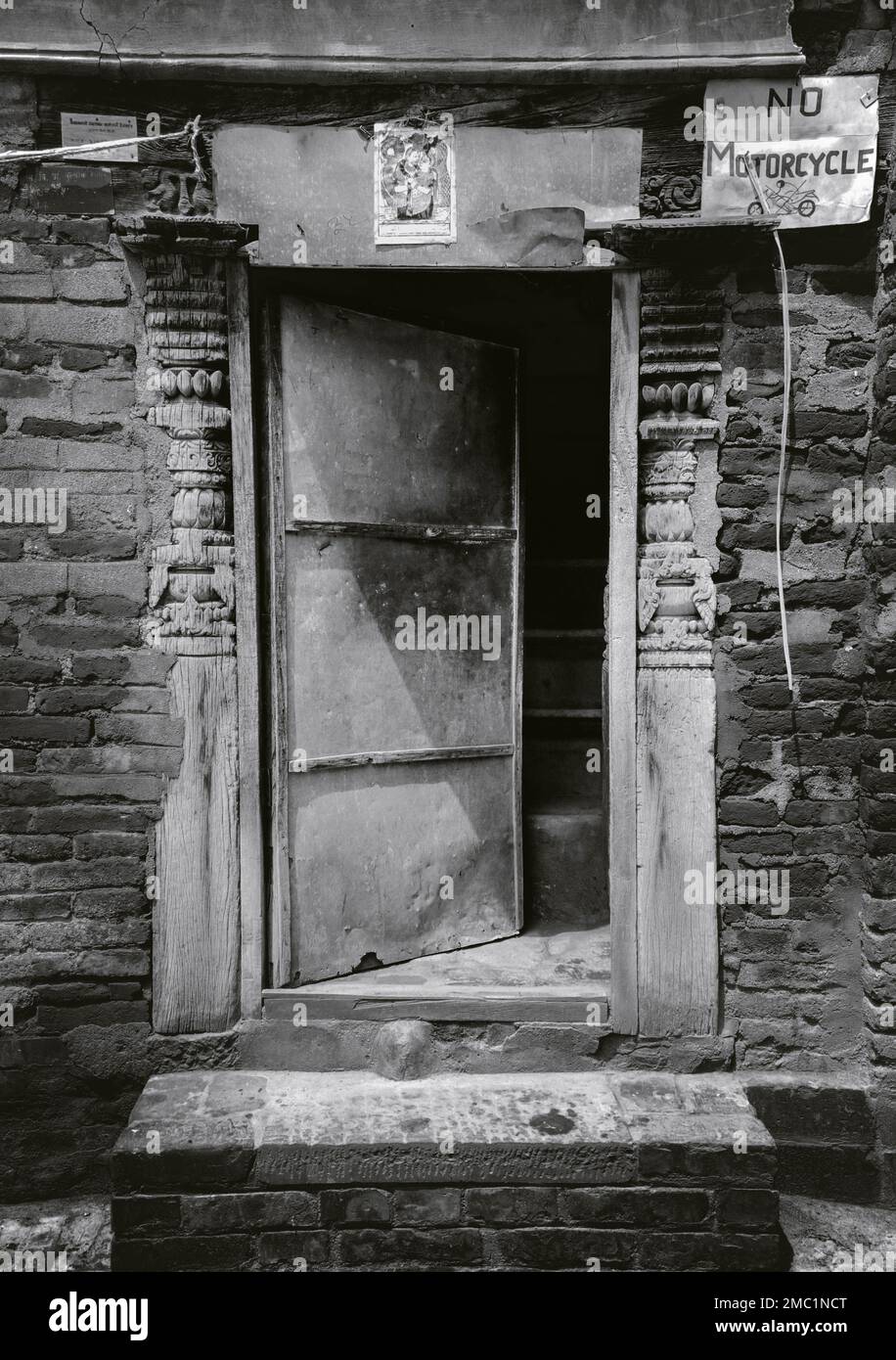 A grayscale of an old grunge door with a "Nor motorcycle" sign hanging ...