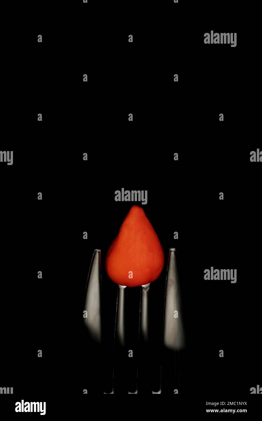 A small red chilli on a fork, food photography in the studio with black ...