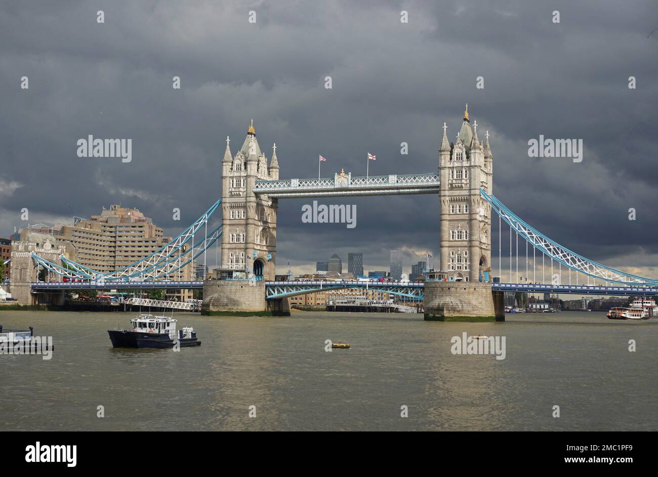 Thames, Tower Bridge in sunlight, dark rain clouds behind, London ...