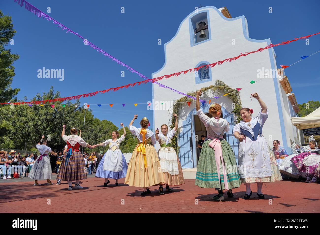 Women in traditional dress dance in front of the Ermita de San Vicent ...