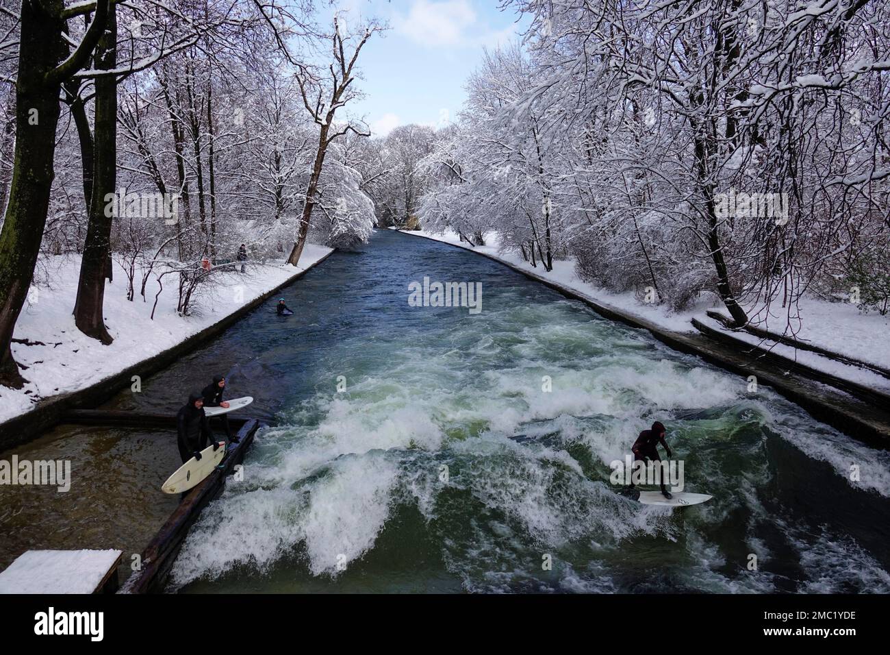Surfers at the Eisbach wave below Prinzregentenstrasse, snow-covered in ...