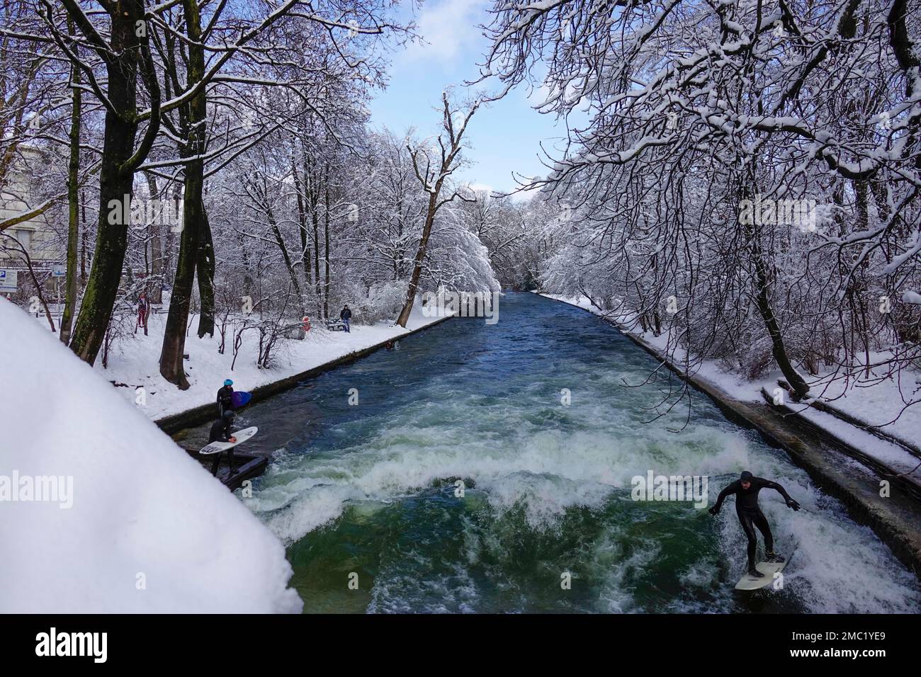 Surfers at the Eisbach wave below Prinzregentenstrasse, snow-covered in ...