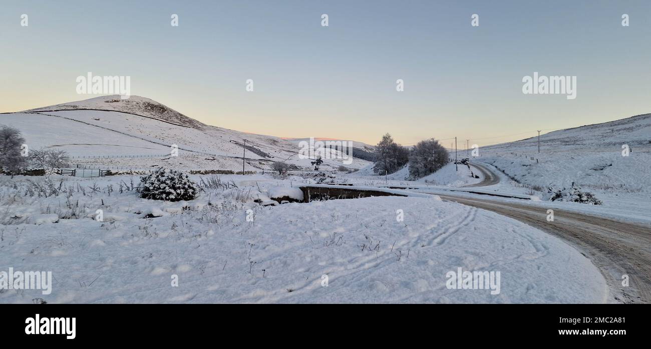 A panoramic view of a mountain range covered with snow during an orange ...