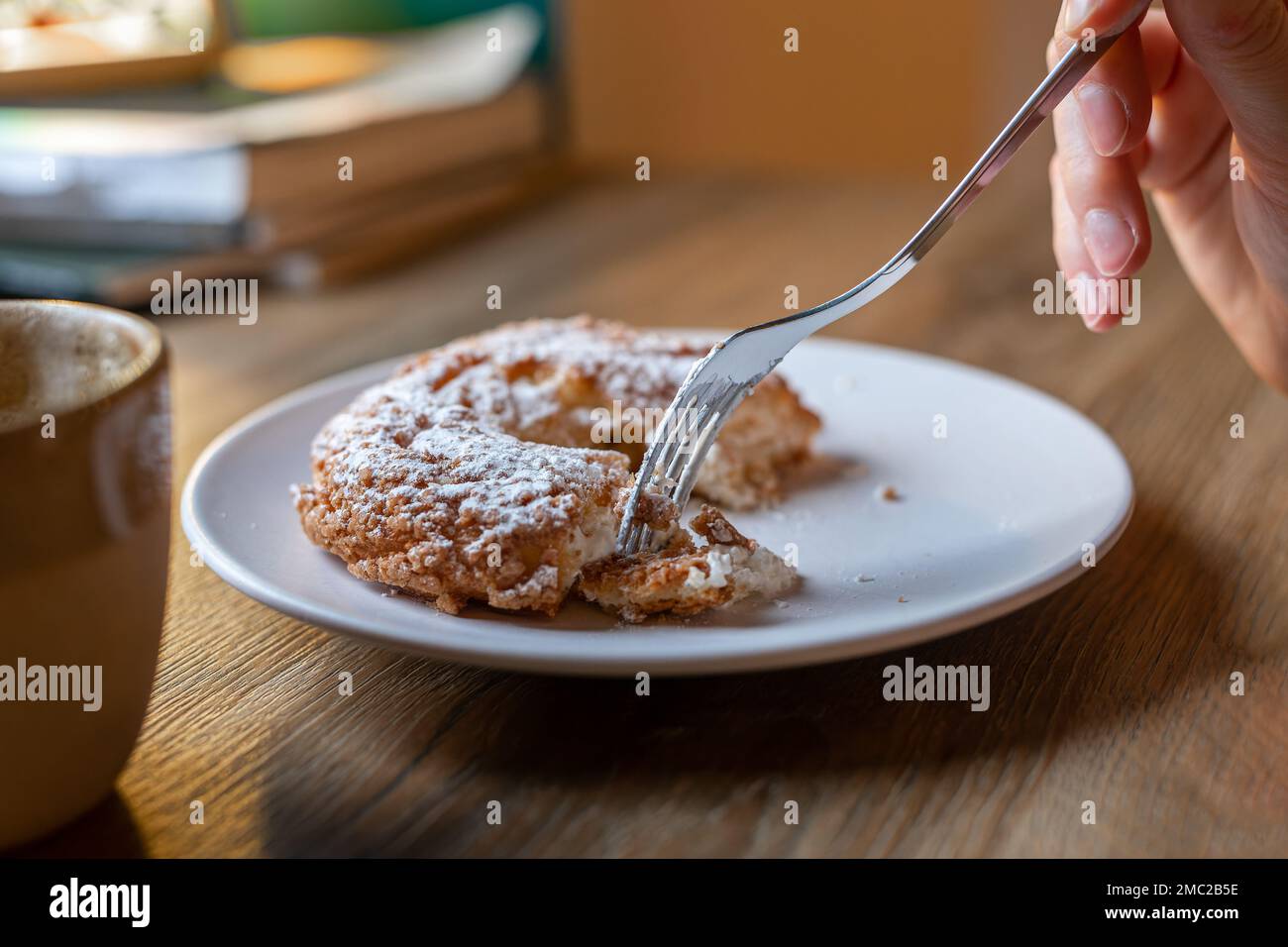 Hands with fork eating sweet sugar dessert in coffee shop at wood table ...