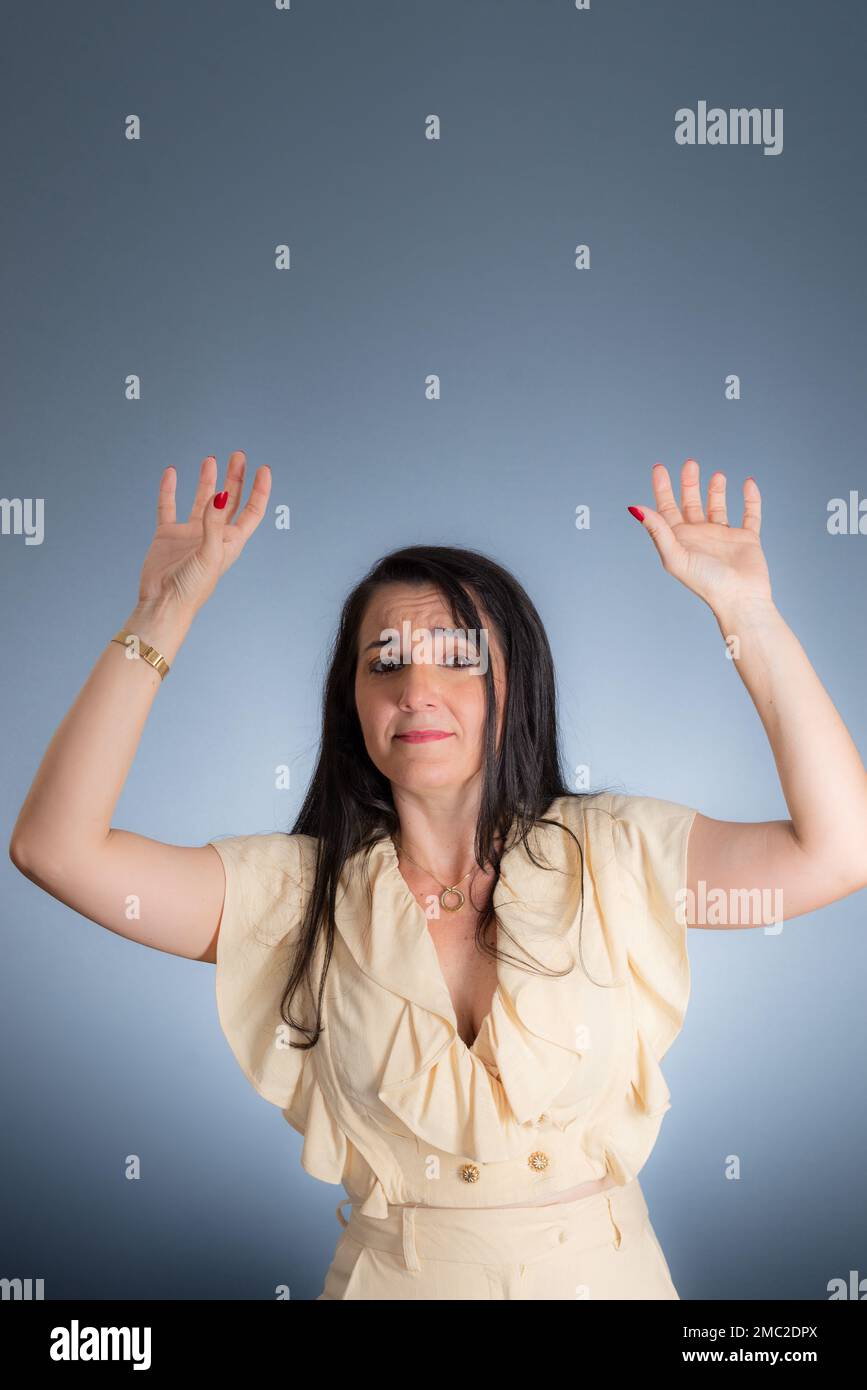 Portrait of young beautiful woman with arms up. Isolated against light ...