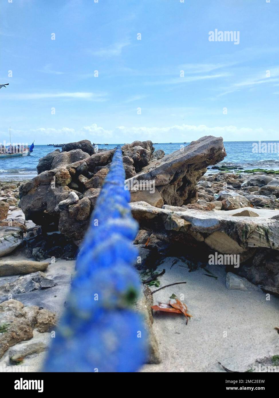 A close up of a rope connected to stacks at a beach, on the sandy shore ...