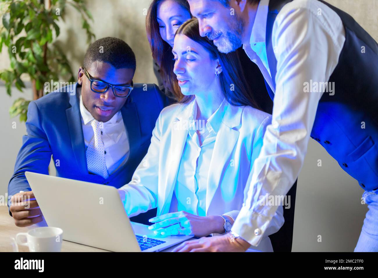 Multiethnic colleagues work together using pc. African mentor explains application aid to ...