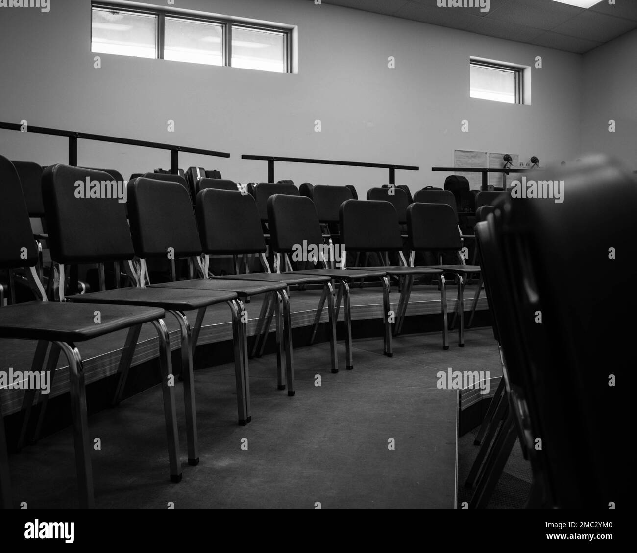 A black and white shot of classroom chairs next to white wall with ...