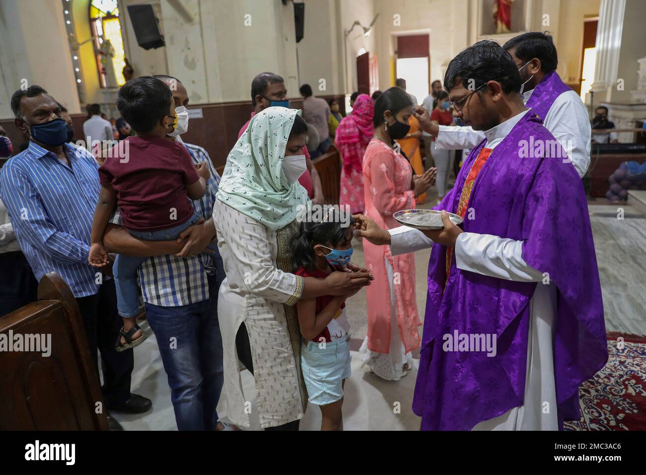 A Catholic priest marks the forehead of a devotee with the symbol of a ...