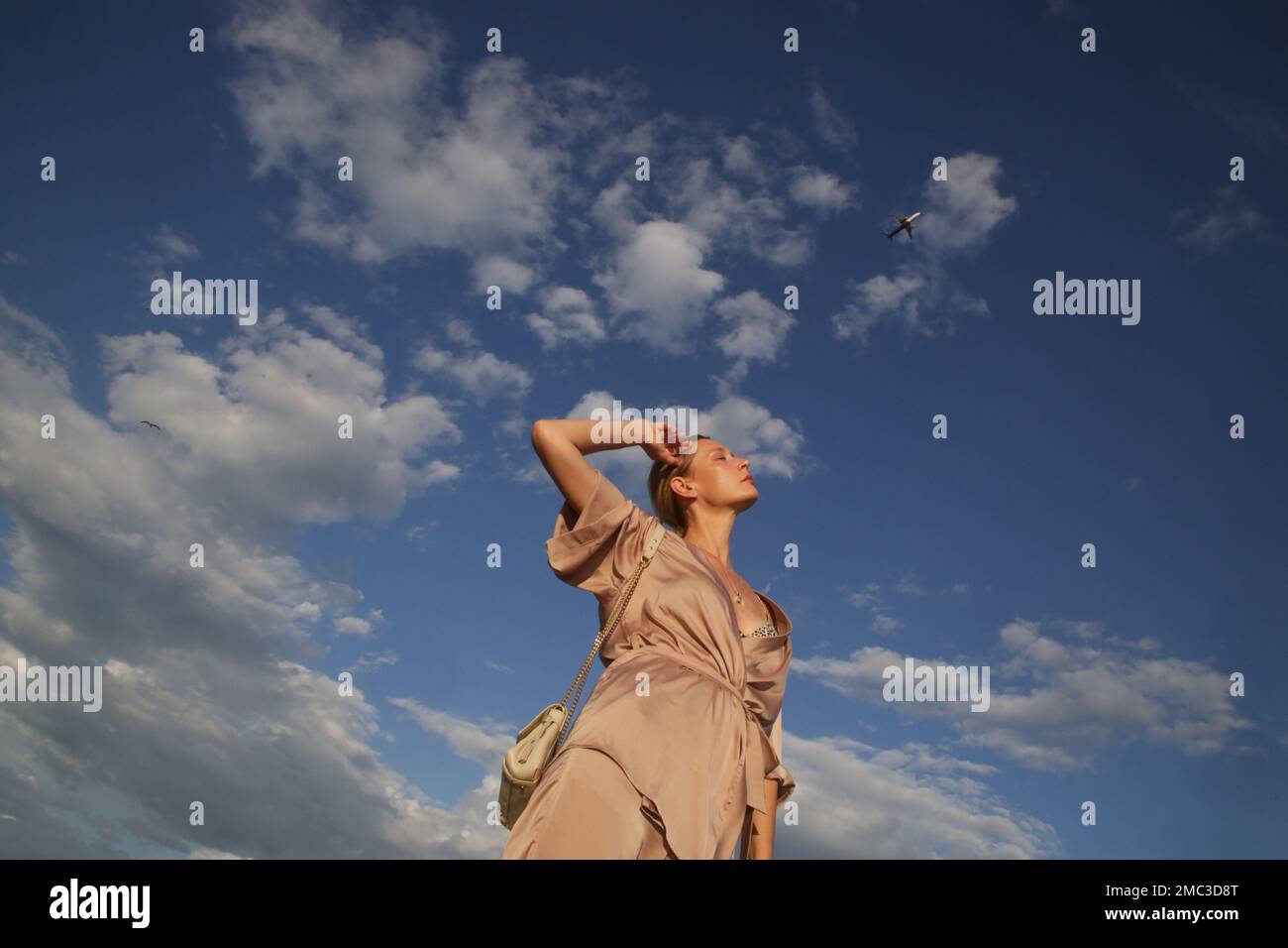 Beautiful young woman raising arms under blue sky, concept of freedom ...