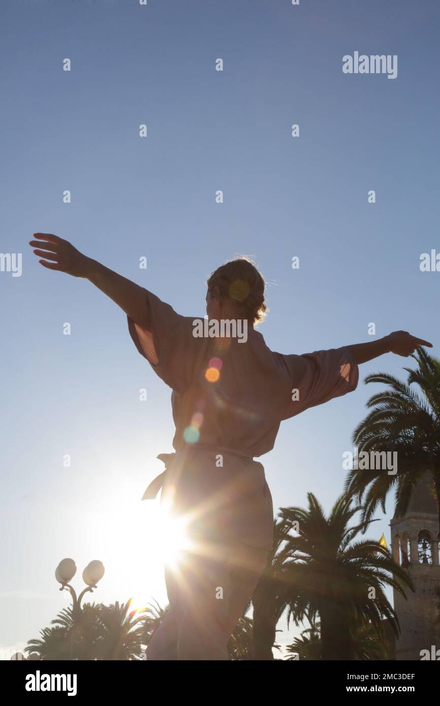 Beautiful young woman raising arms under blue sky, concept of freedom ...