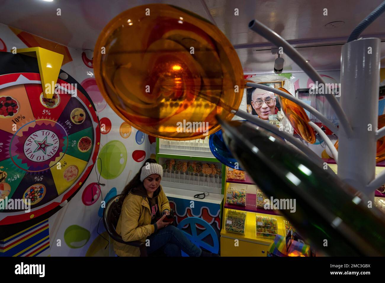 A shop attendant sits in a newly opened candy store where a portrait of ...