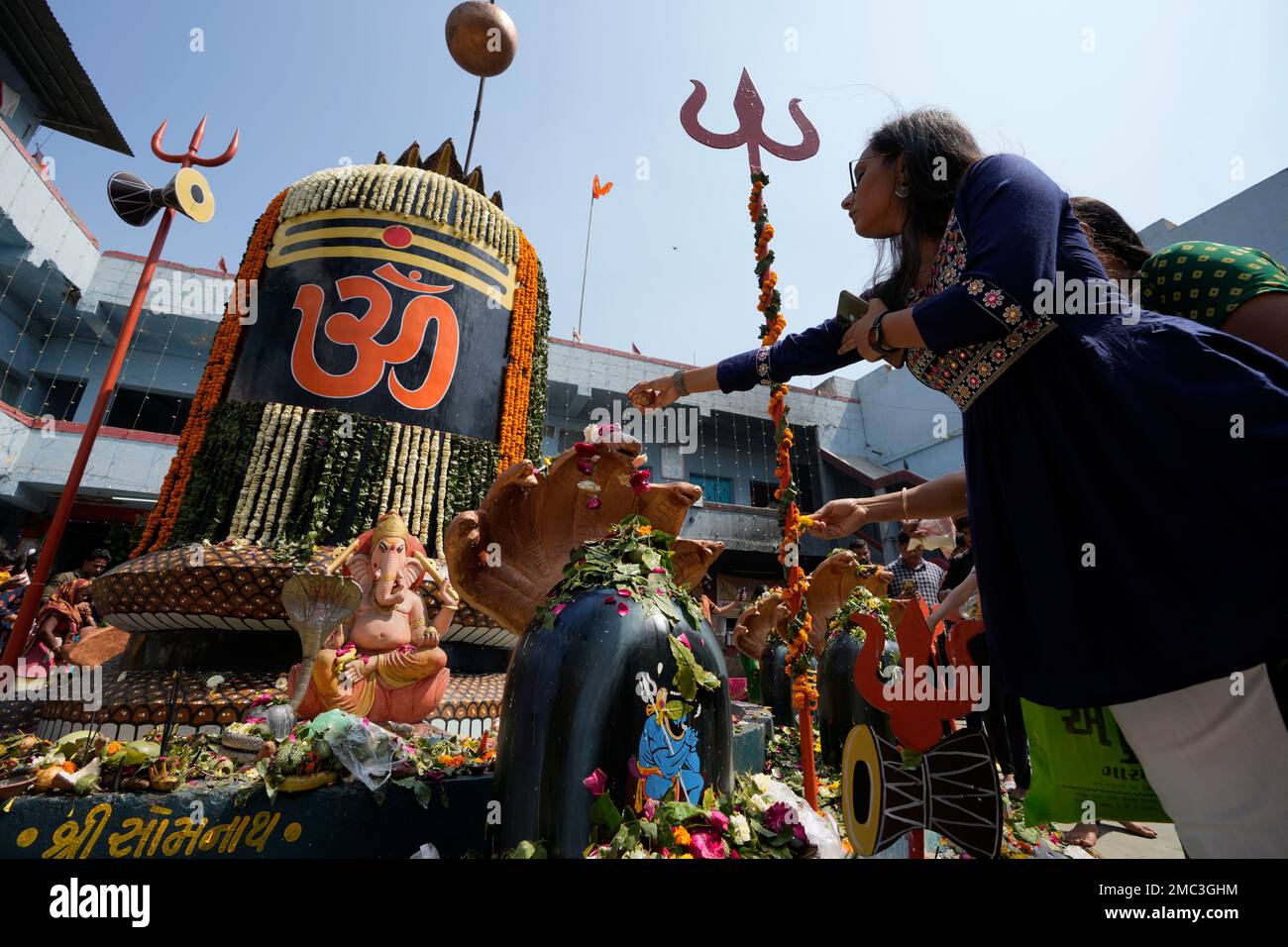 Hindu devotees perform rituals around a Shivling, a representation of ...