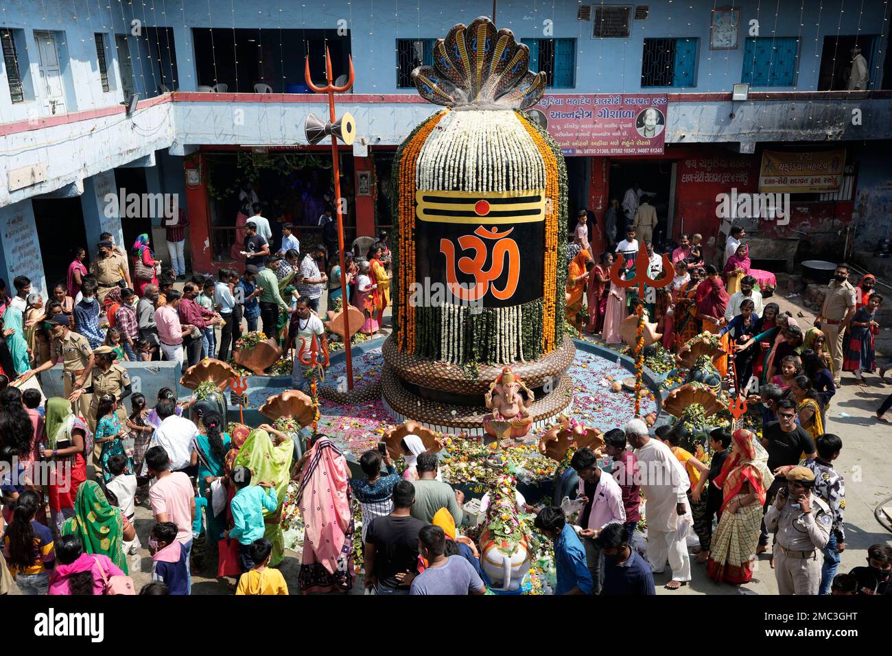 Hindu devotees perform rituals around a Shivling, a representation of ...