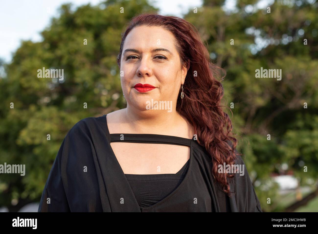 Portrait of a plus-size woman looking at camera in nature background ...