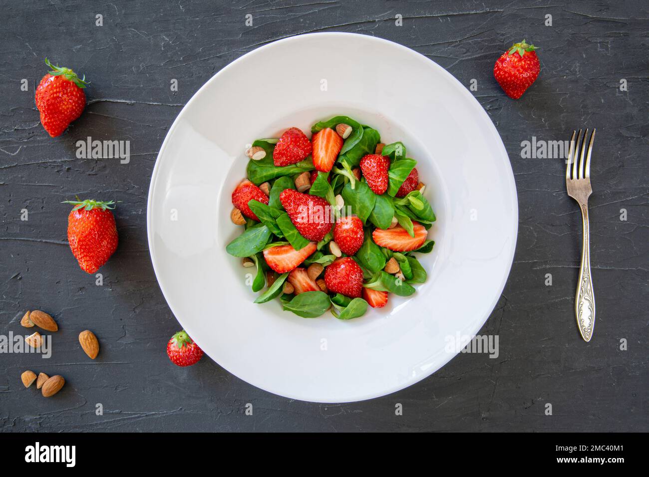 Healthy salad with nuts and berries on black table, top view Stock ...