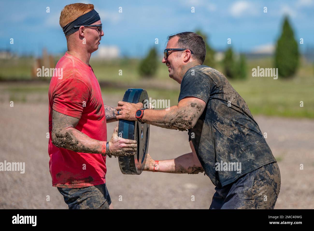 Participants of the Filthy Mudder Mud Run trade off a 45-lb plate June ...