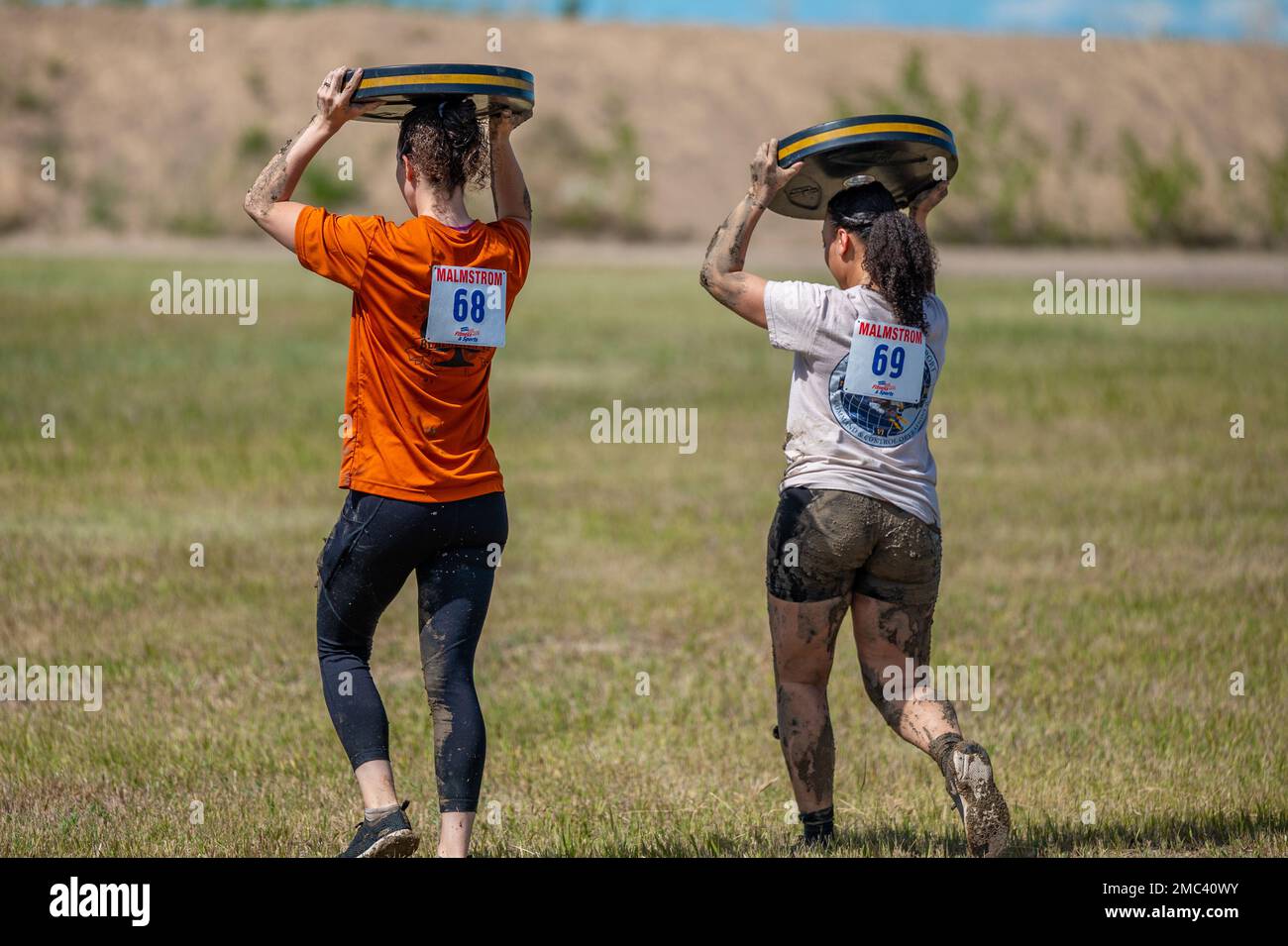Participants of the Filthy Mudder Mud Run carry 35-lb plates over their ...