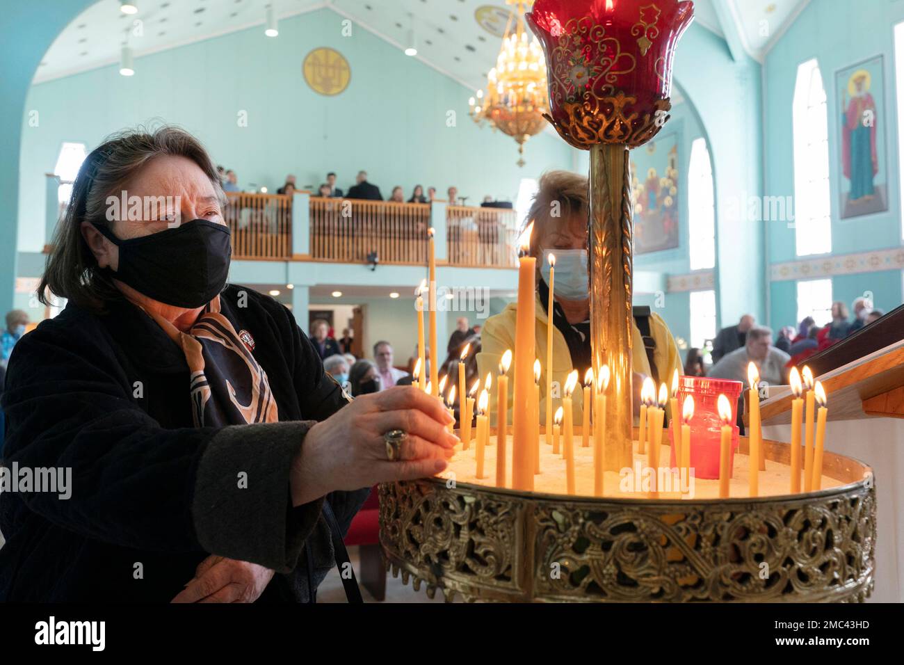 A woman lights a candle during the Mass at St. Andrew Ukrainian ...