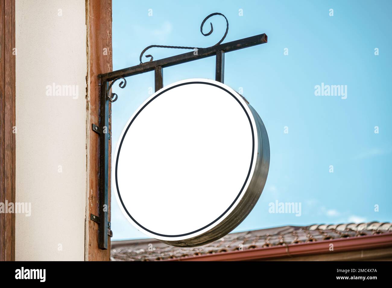 Blank signboard mockup hanging on the wall of the store in the street ...