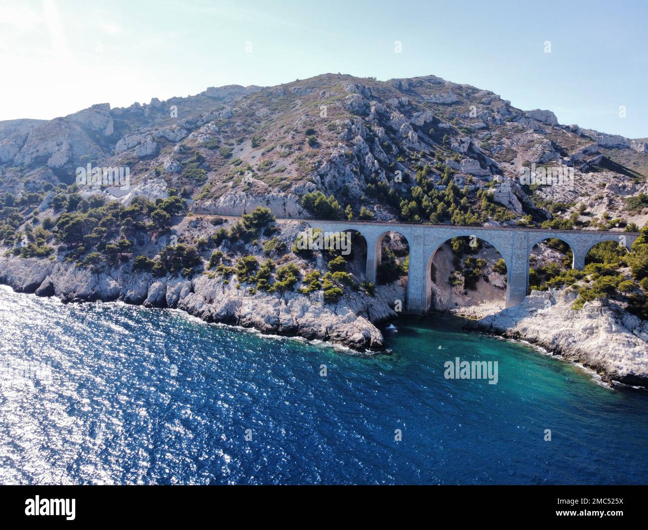 An aerial of a bridge near a beautiful sea with a tall mountain in the ...