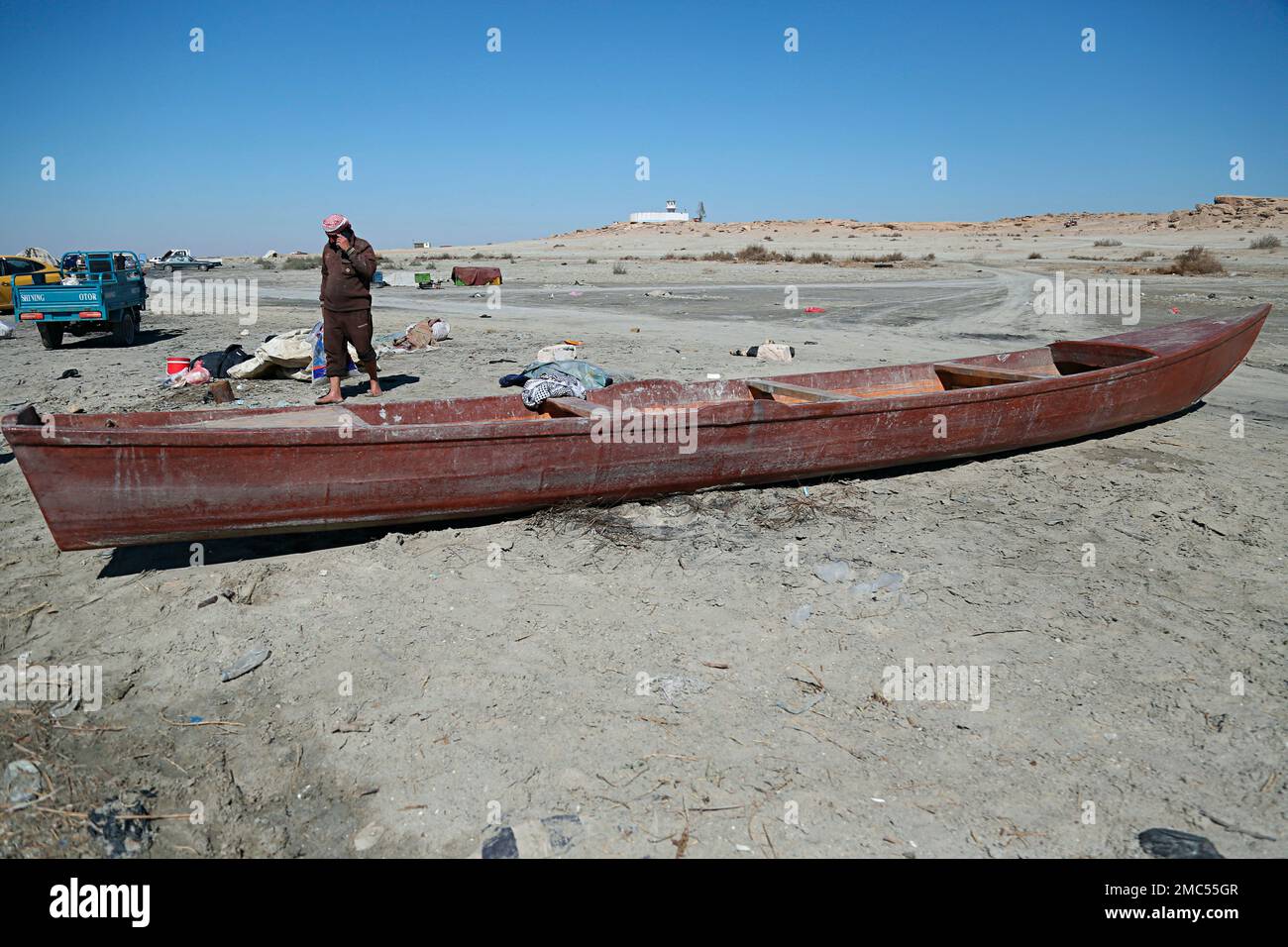 An Iraqi fisherman walks beside his boat on the banks of Razzaza Lake ...