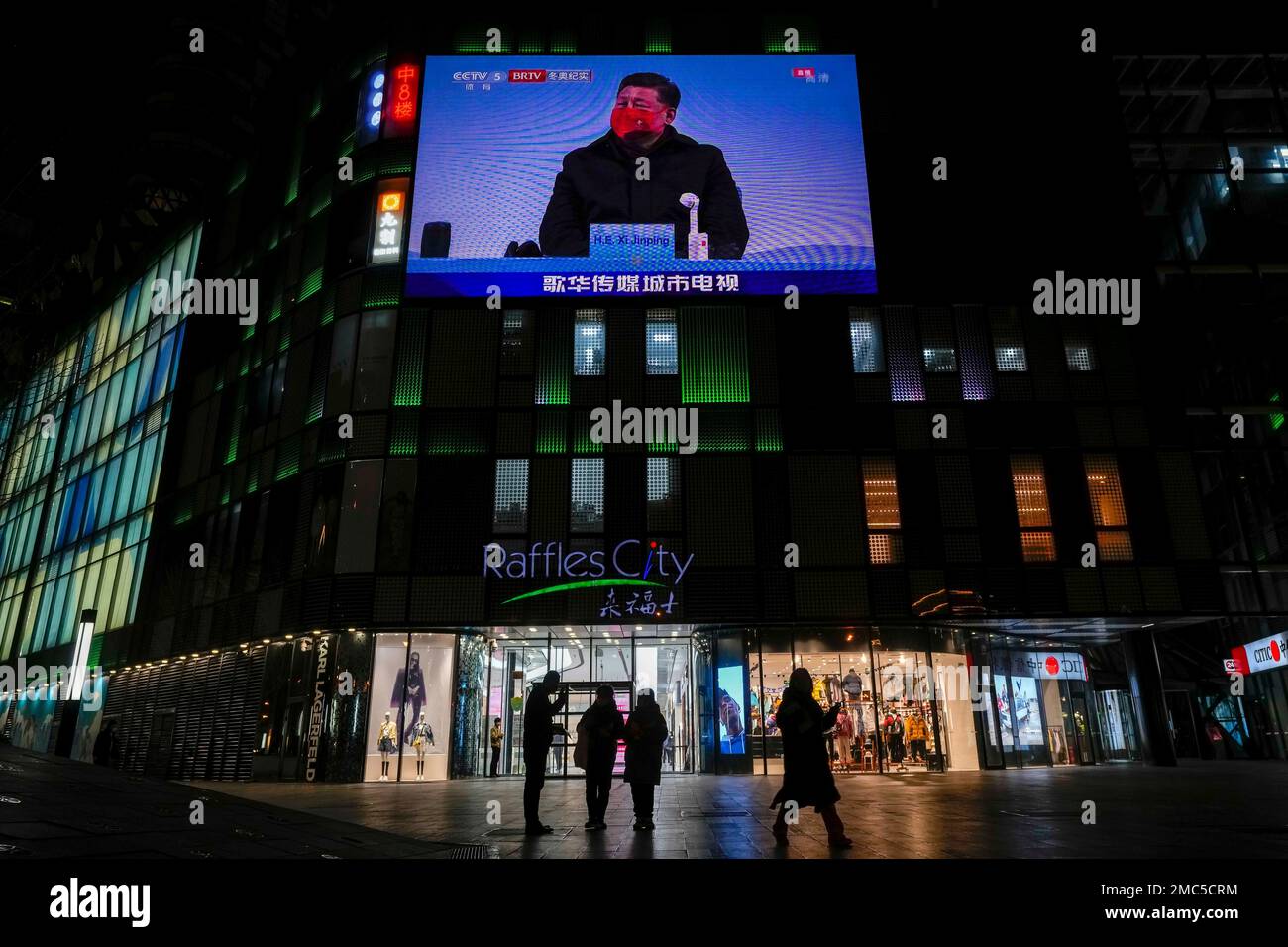 Residents walk by a screen showing Chinese President Xi Jinping wearing ...