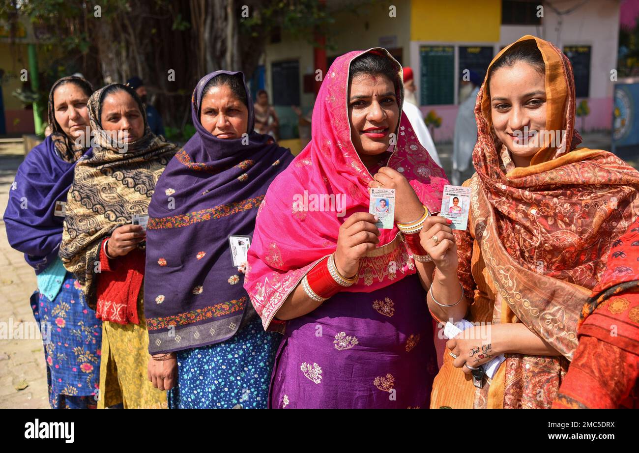 Village women display their voter identity cards as they arrive to cast ...