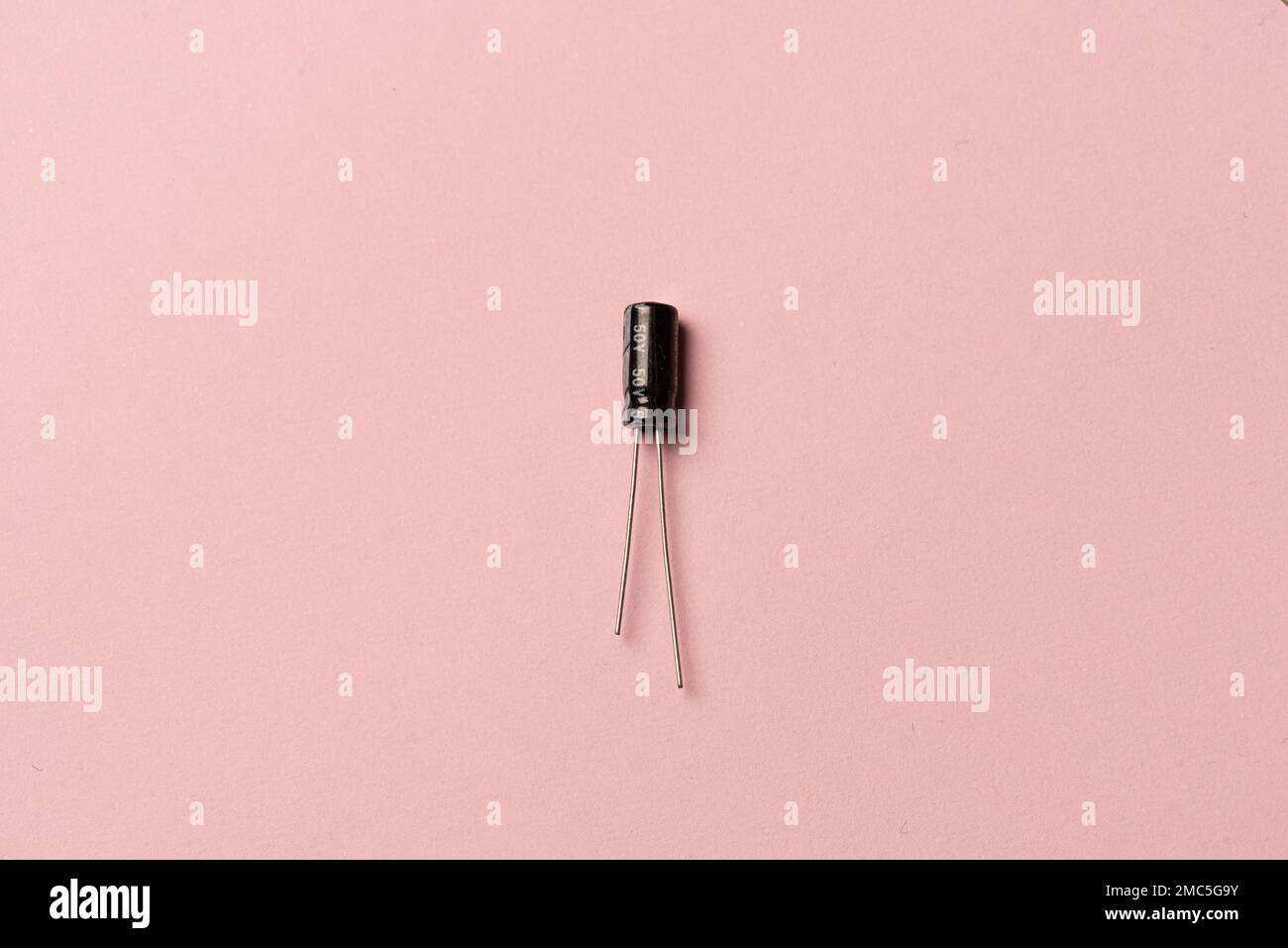 A black small capacitor on pink background Stock Photo - Alamy