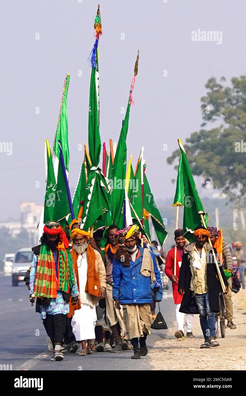 Muslim devotees carrying religious flags walk along a road as they ...
