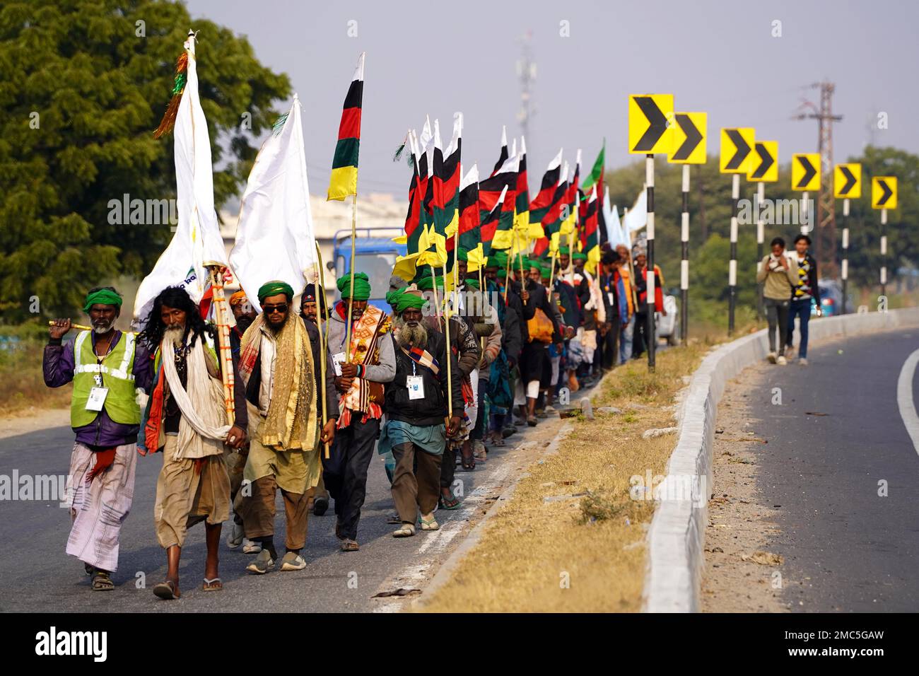 Muslim devotees carrying religious flags walk along a road as they ...