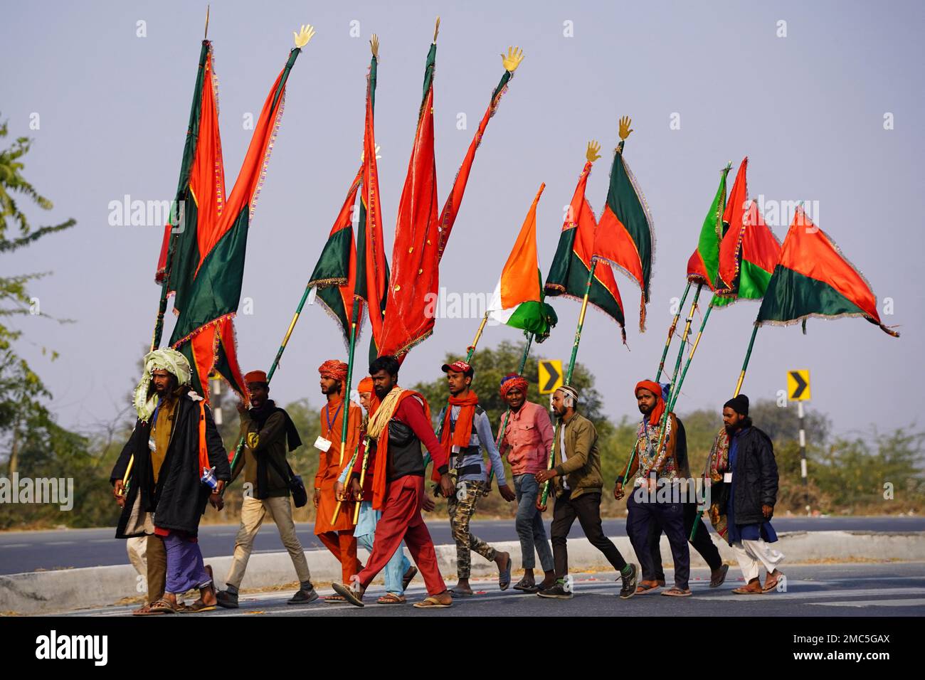 Muslim devotees carrying religious flags walk along a road as they ...