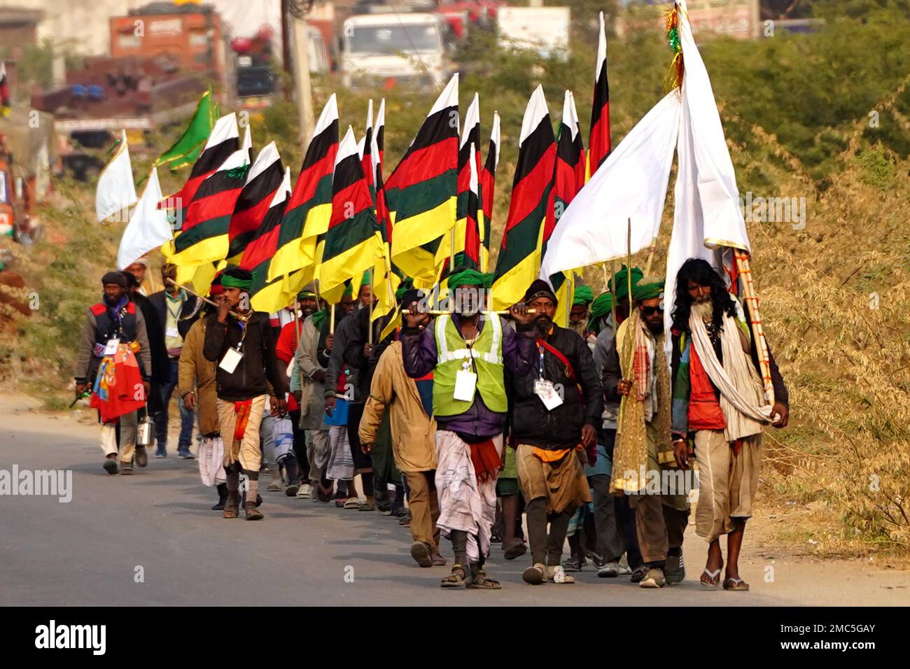 Muslim devotees carrying religious flags walk along a road as they ...