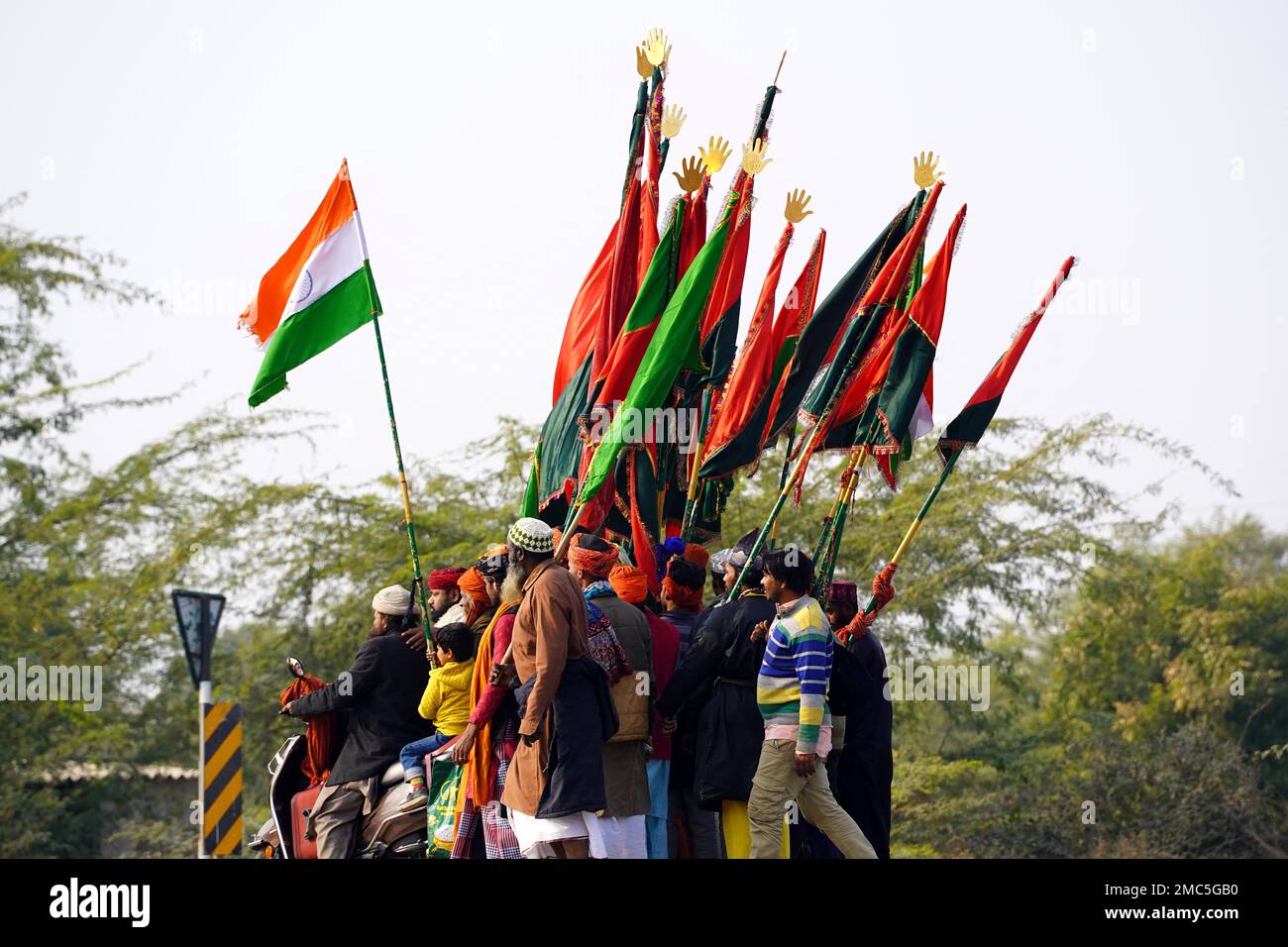 Muslim devotees carrying religious flags walk along a road as they ...