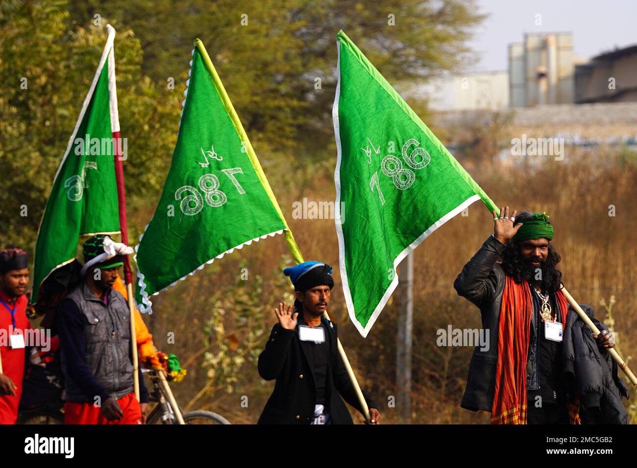 Muslim devotees carrying religious flags walk along a road as they ...