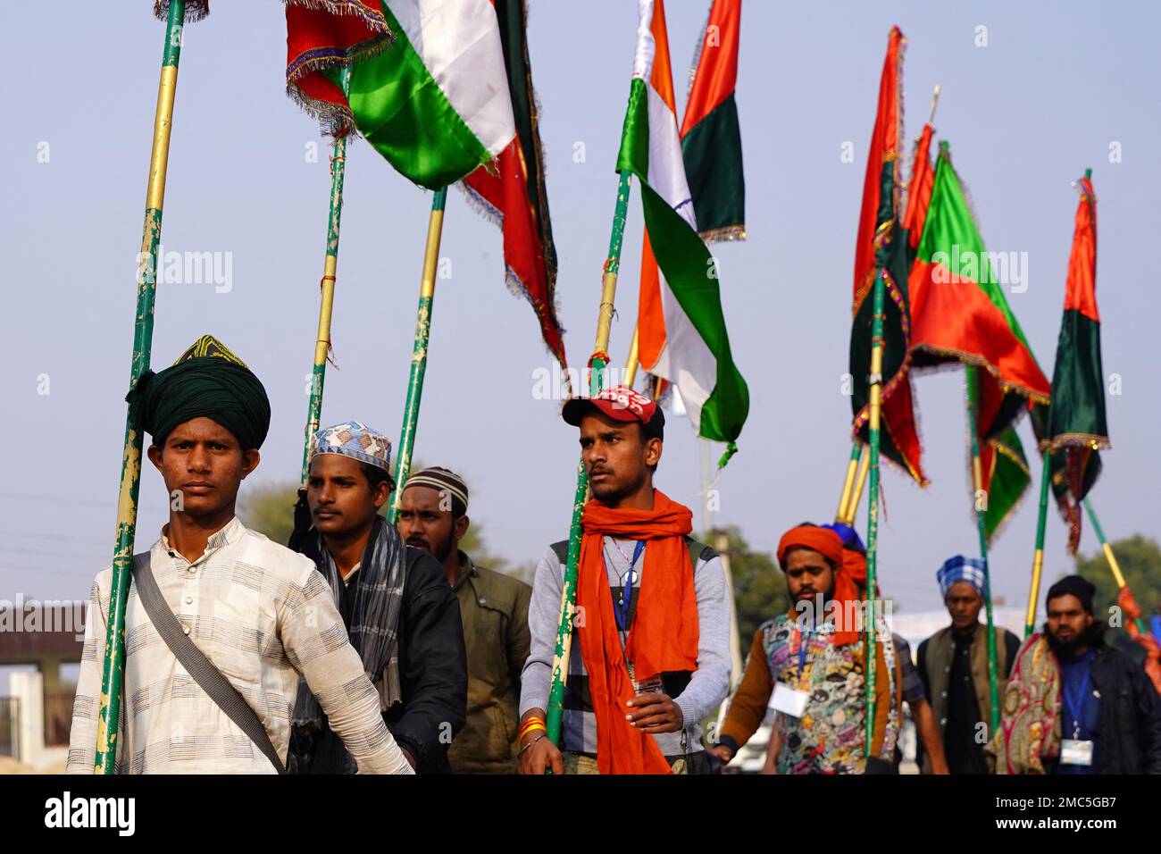 Muslim devotees carrying religious flags walk along a road as they ...