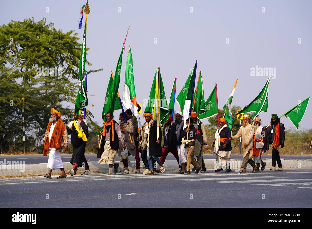 Muslim devotees carrying religious flags walk along a road as they ...