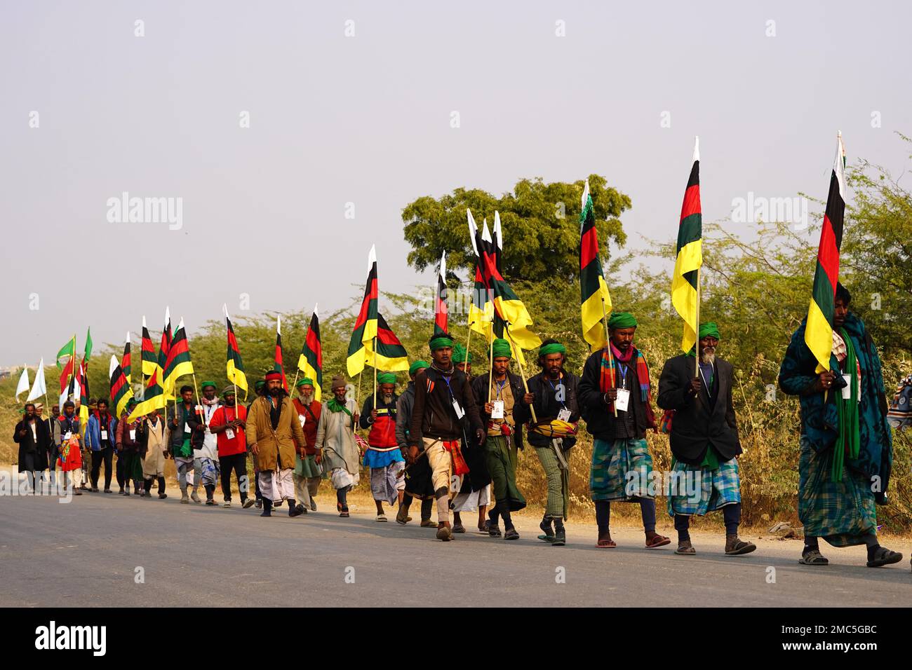 Muslim devotees carrying religious flags walk along a road as they ...