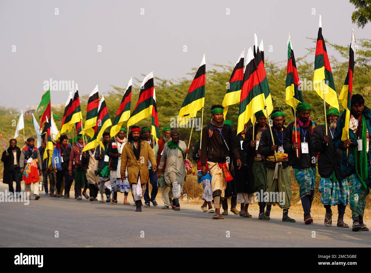 Muslim devotees carrying religious flags walk along a road as they ...