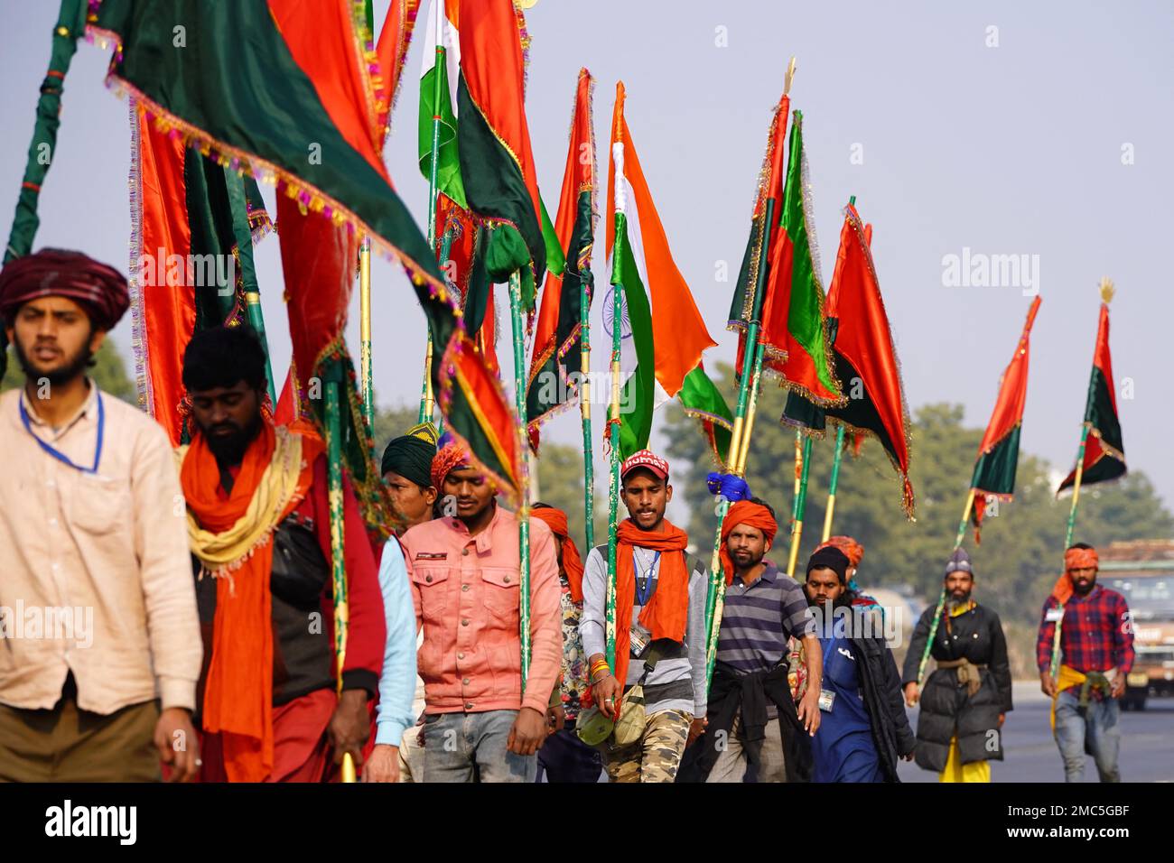 Muslim devotees carrying religious flags walk along a road as they ...
