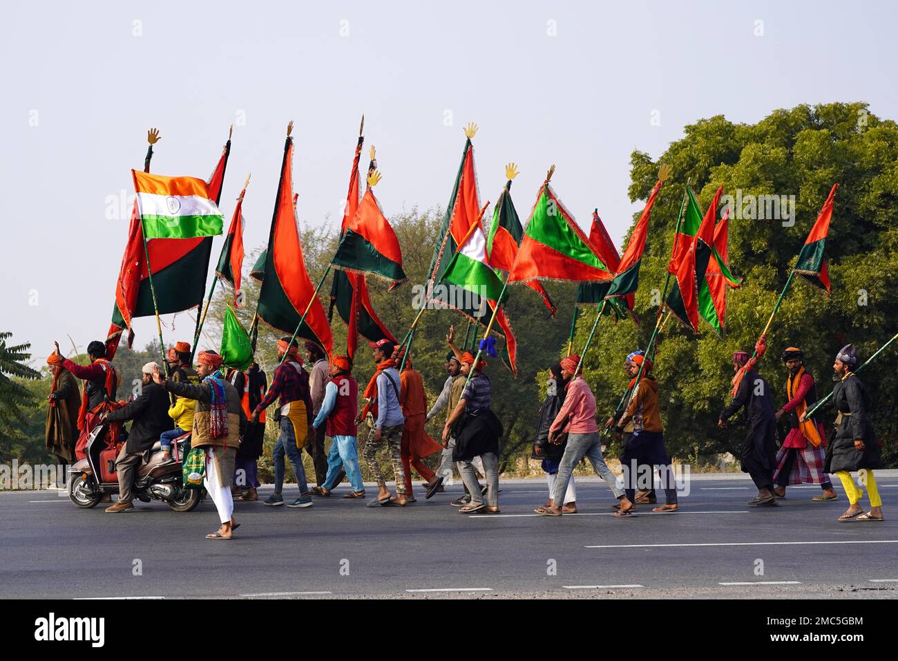 Muslim devotees carrying religious flags walk along a road as they ...