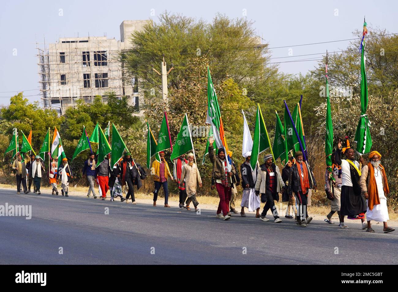 Muslim devotees carrying religious flags walk along a road as they ...