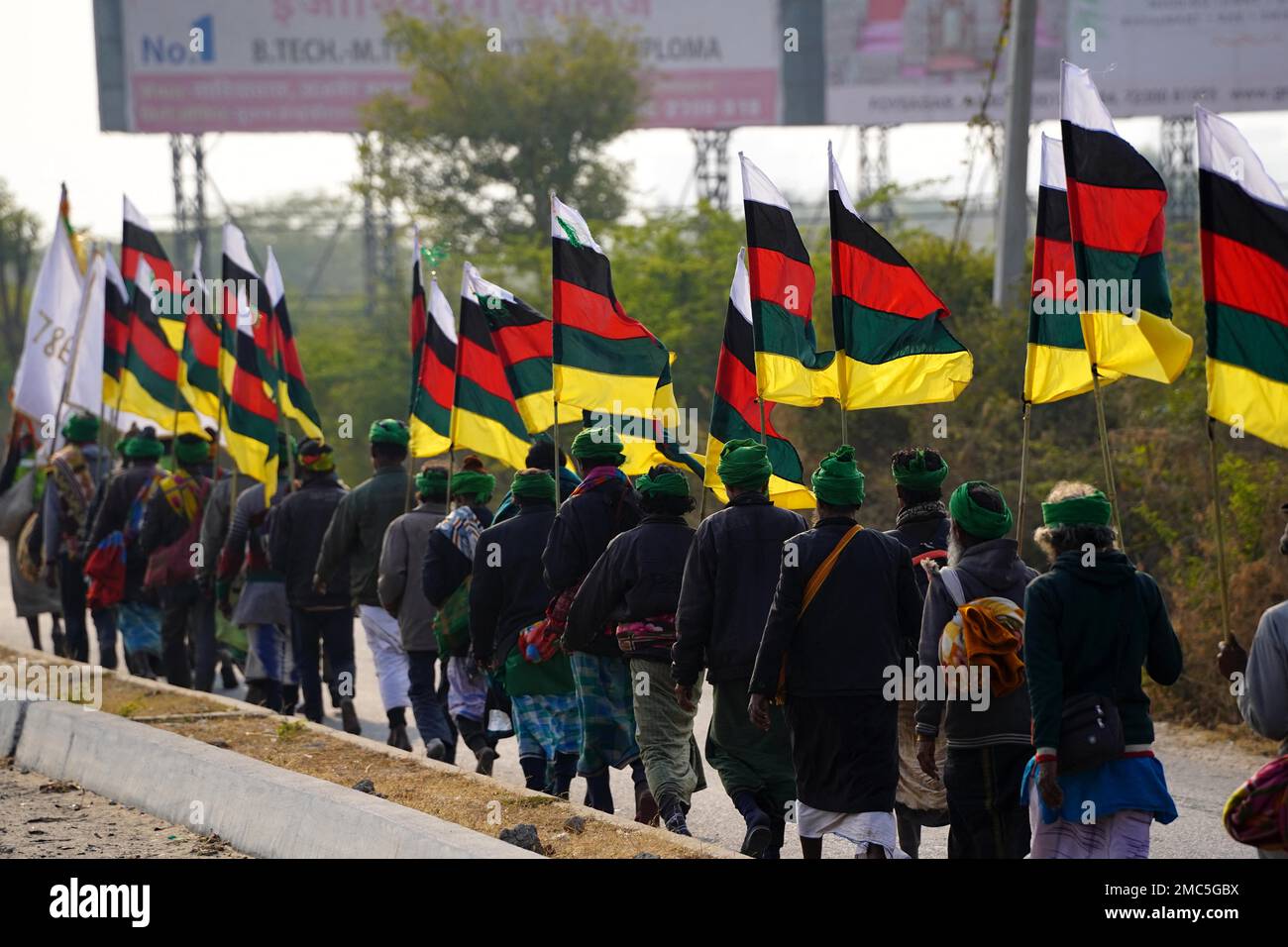 Muslim devotees carrying religious flags walk along a road as they ...