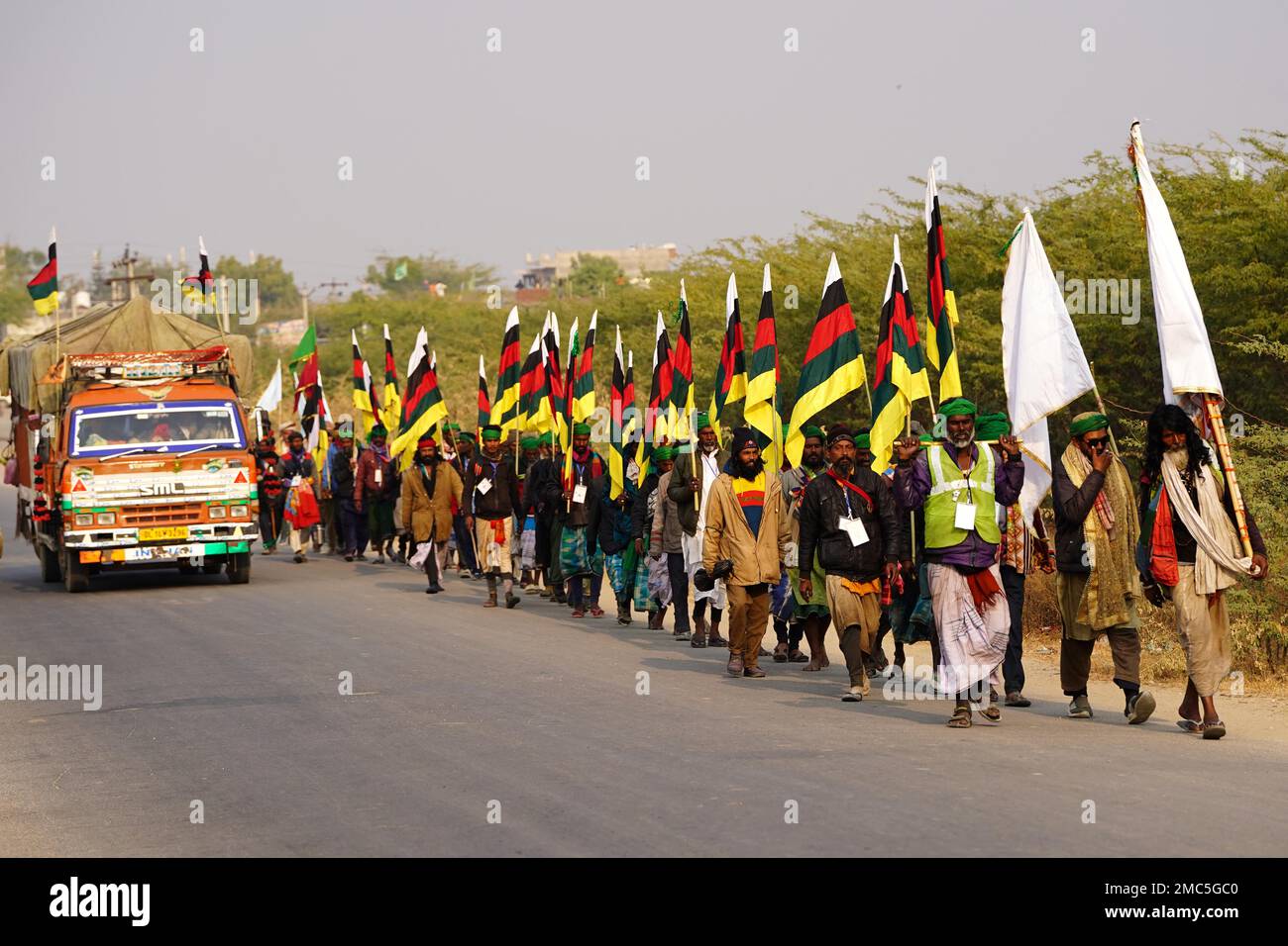 Muslim devotees carrying religious flags walk along a road as they ...