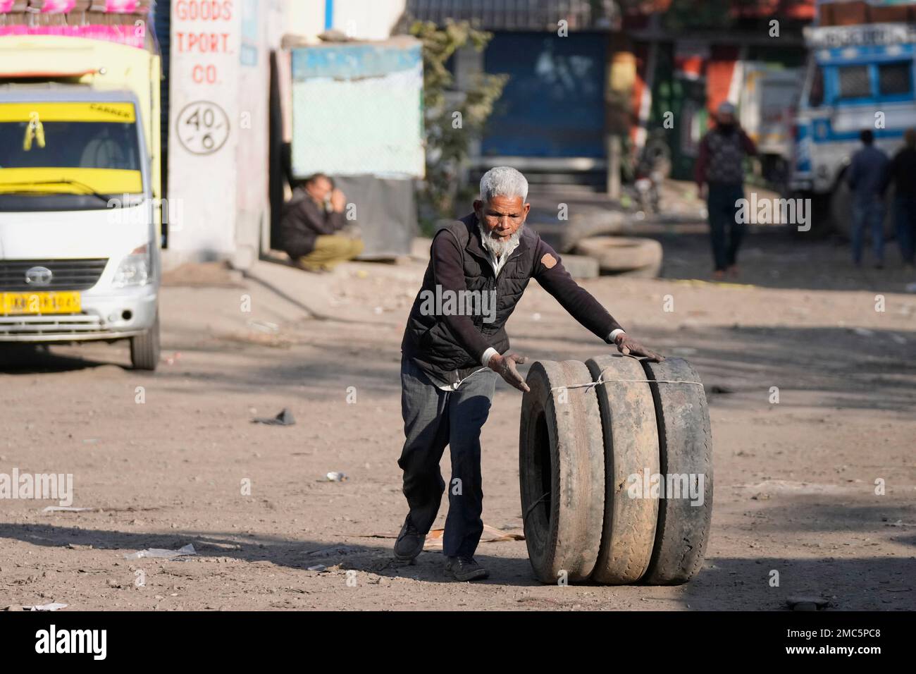 An Indian laborer pushes tires for a recyclable shop at a yard on the ...