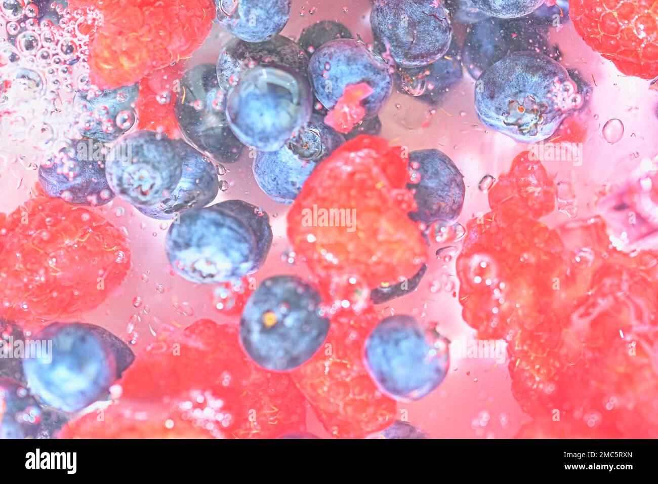 Blueberries and raspberries in liquid with bubbles. Colourful ripe ...