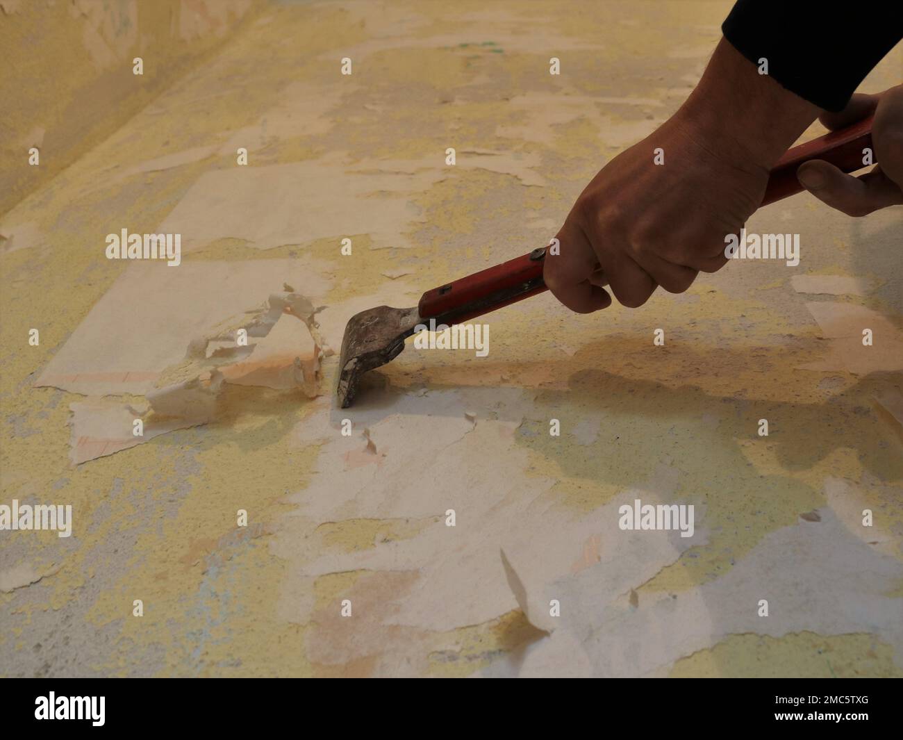male hands are scraping a surface with the remnants of old peeled ...