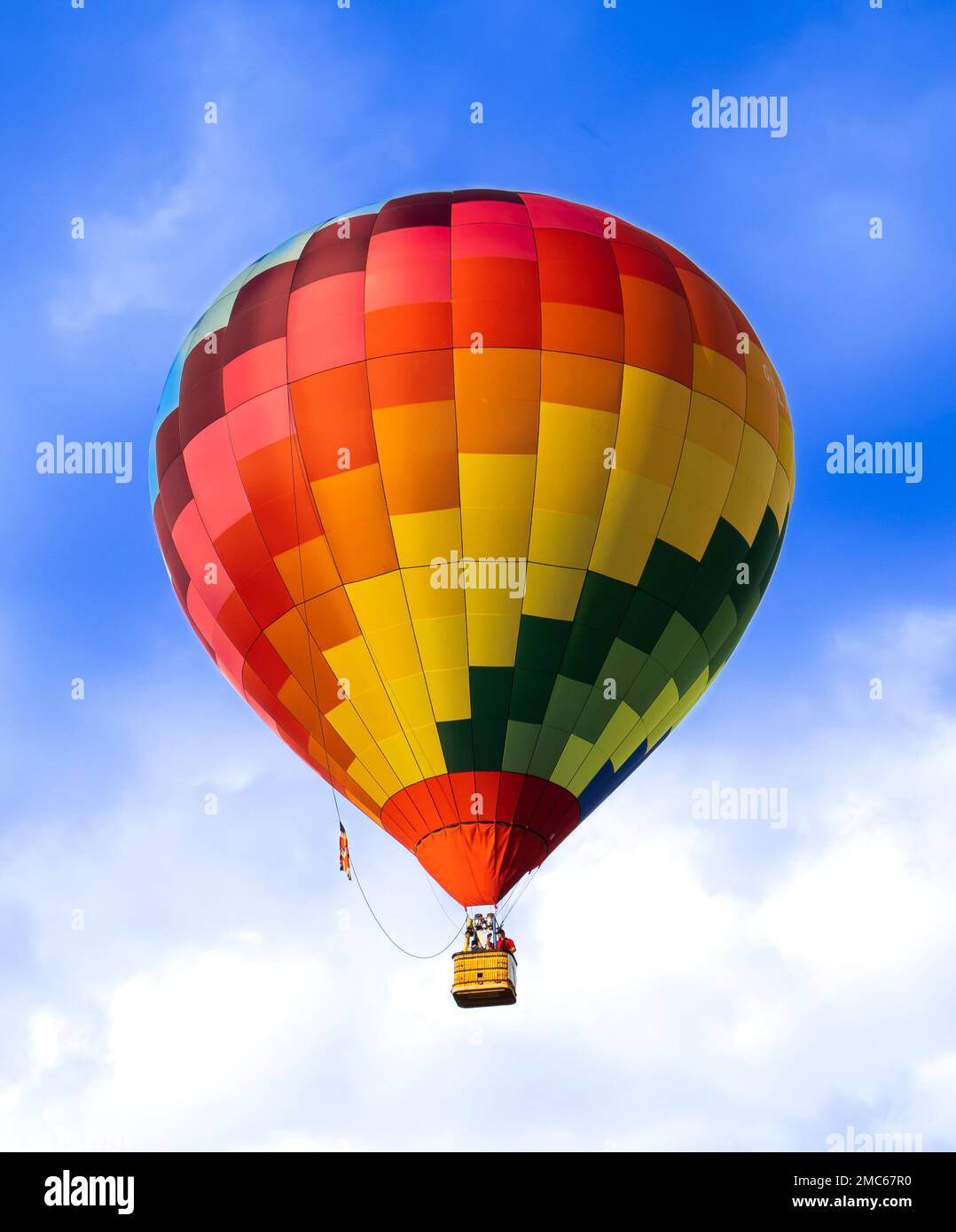 Rainbow color hot air balloon on a beautiful light clouded blue sky Stock Photo - Alamy